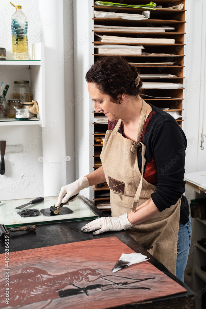 Female artisan in glove using braver and spreading ink on sheet for ...