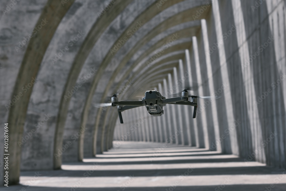 Modern drone flying in empty arched walkway with columns casting ...