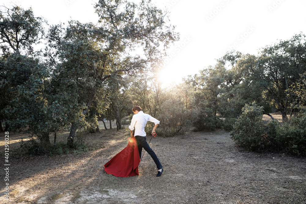 Slim unrecognizable male bullfighter in black pants and white shirt ...
