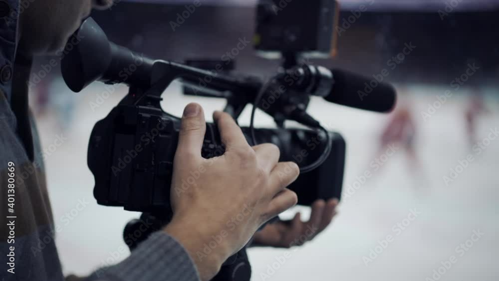 Close-up on cameraman shooting ice hockey game. Camera operator ...