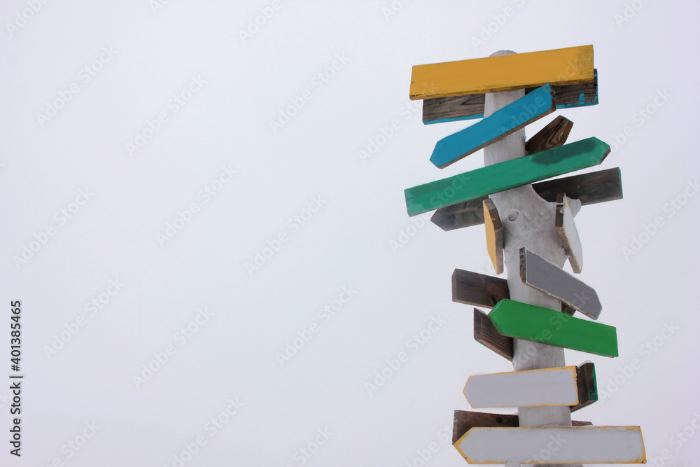 Multicolored handmade crossroad signpost on white sky background. Close ...