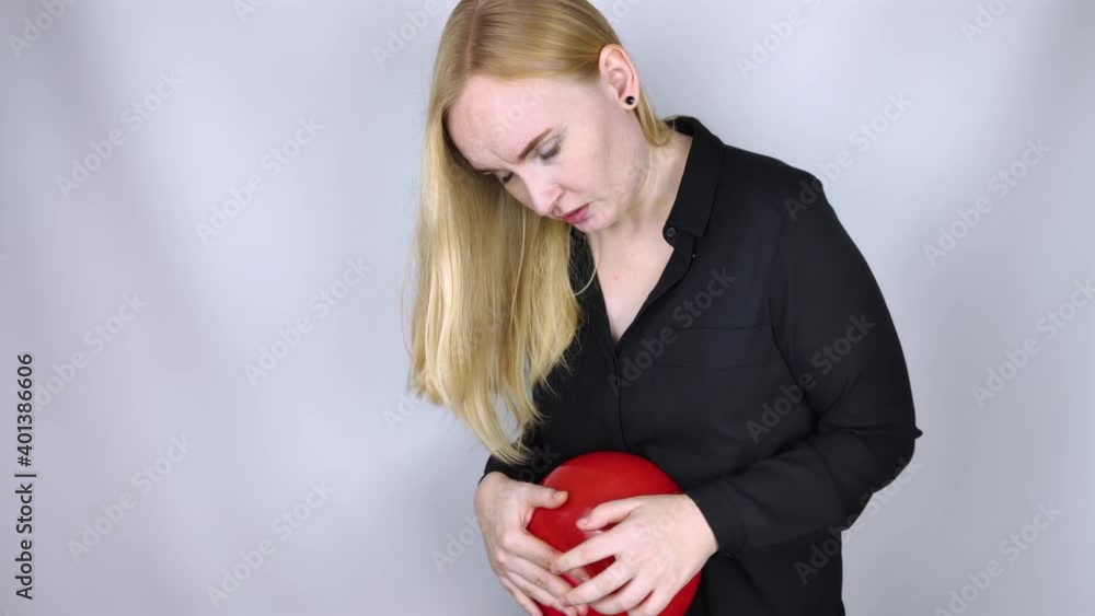 Bloating and flatulence concept. The woman holds a red balloon near the ...