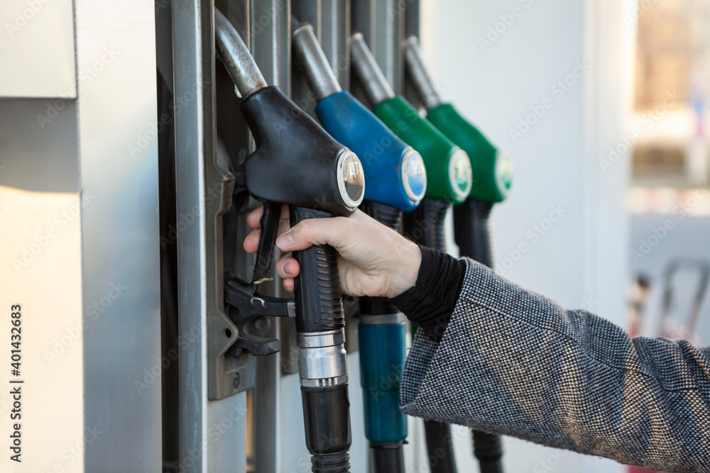 Human hand holding fueling nozzle with diesel on gas station, close-up ...