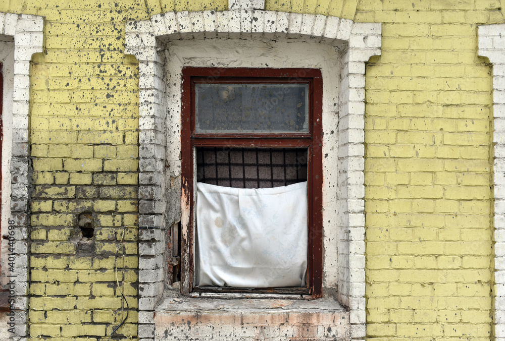 Broken window of an old brick house covered with white cloth. Patient ...