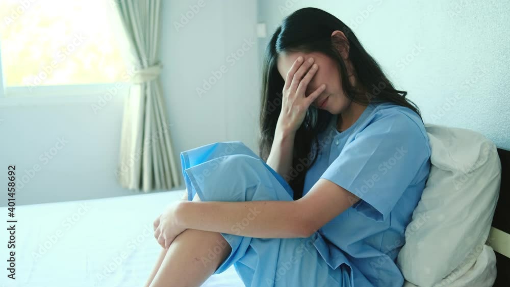 Young woman patient lying at hospital bed feeling sad and depressed ...
