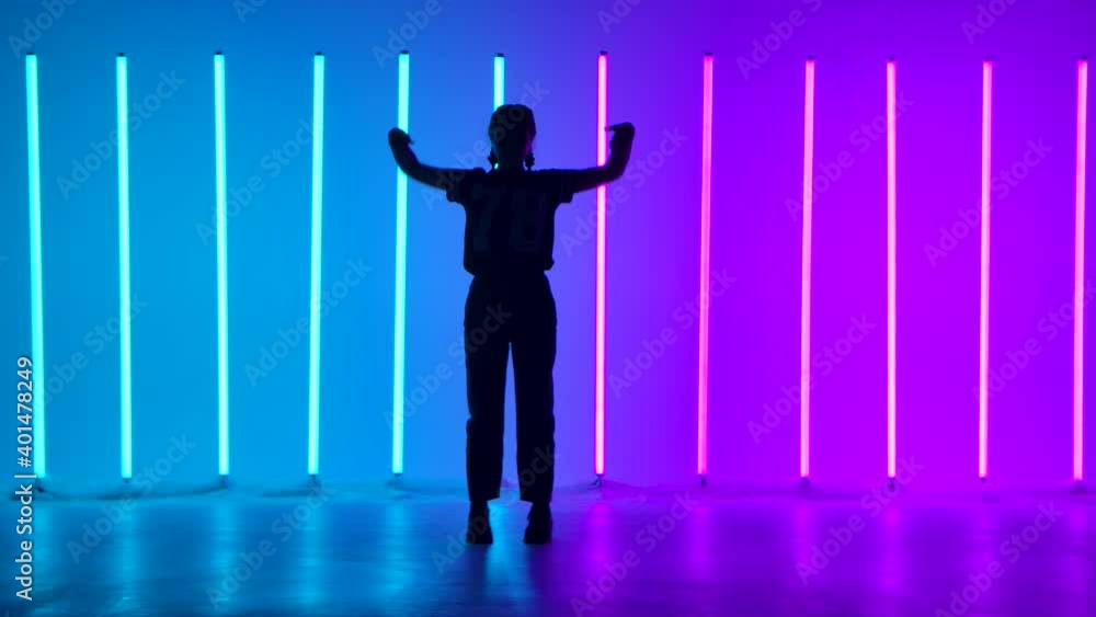Young woman dancing street dance hip hop in a studio with neon lighting ...