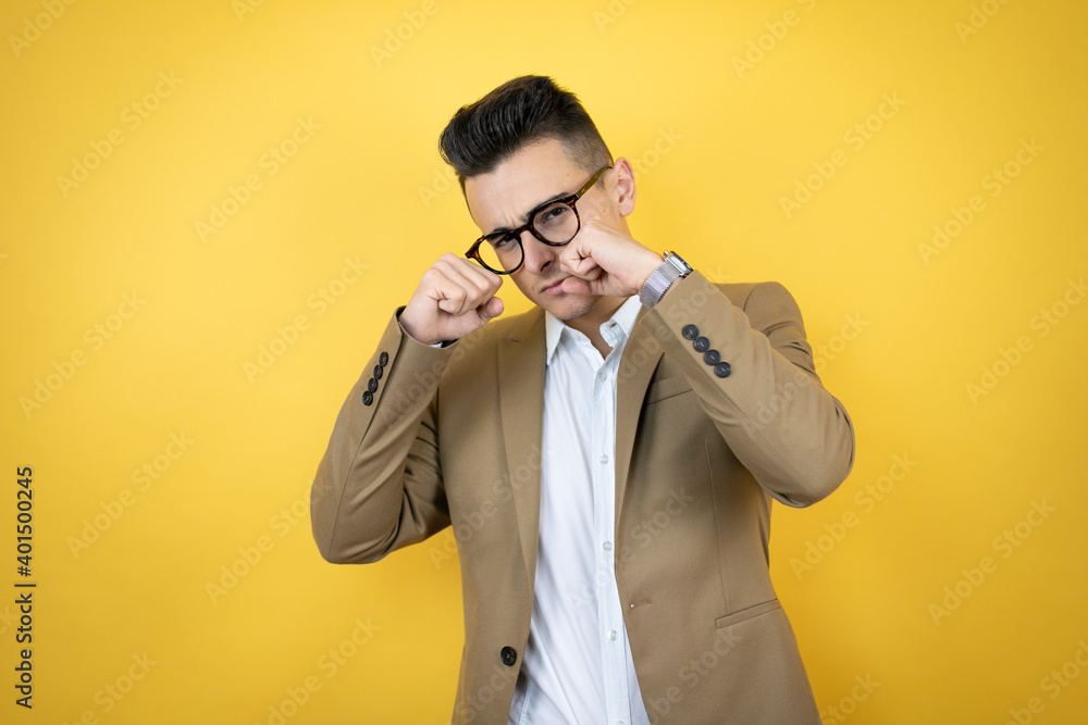 Young business man over isolated yellow background depressed and worry ...