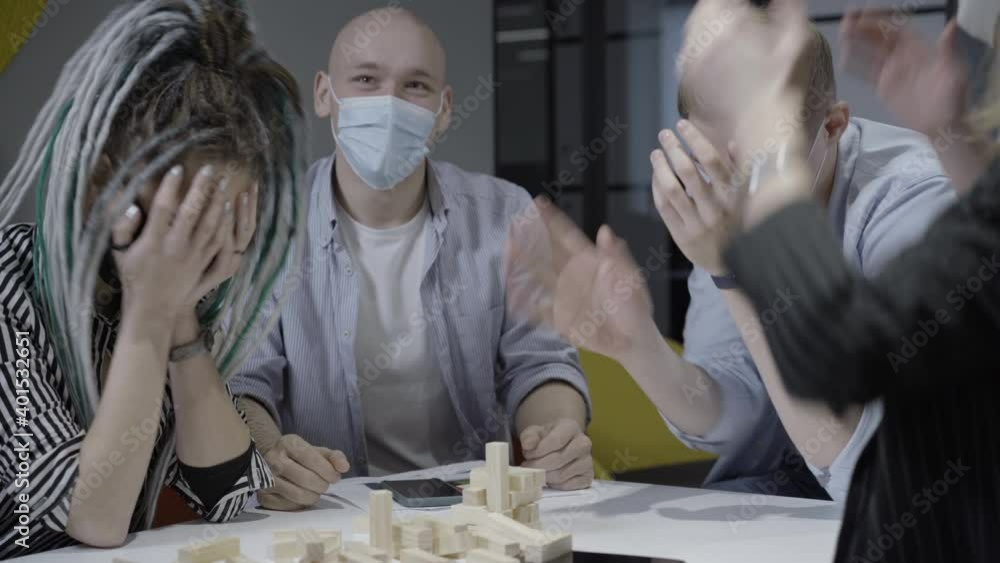 Relaxed positive group of coworkers in Covid-19 face masks playing ...