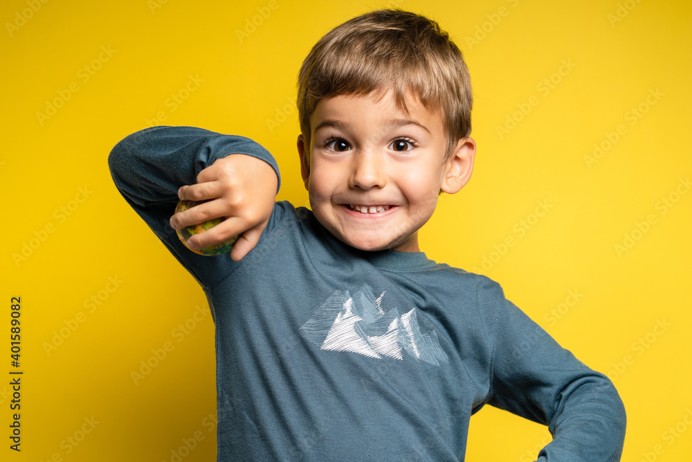Front view portrait of small playful caucasian boy in front of yellow ...