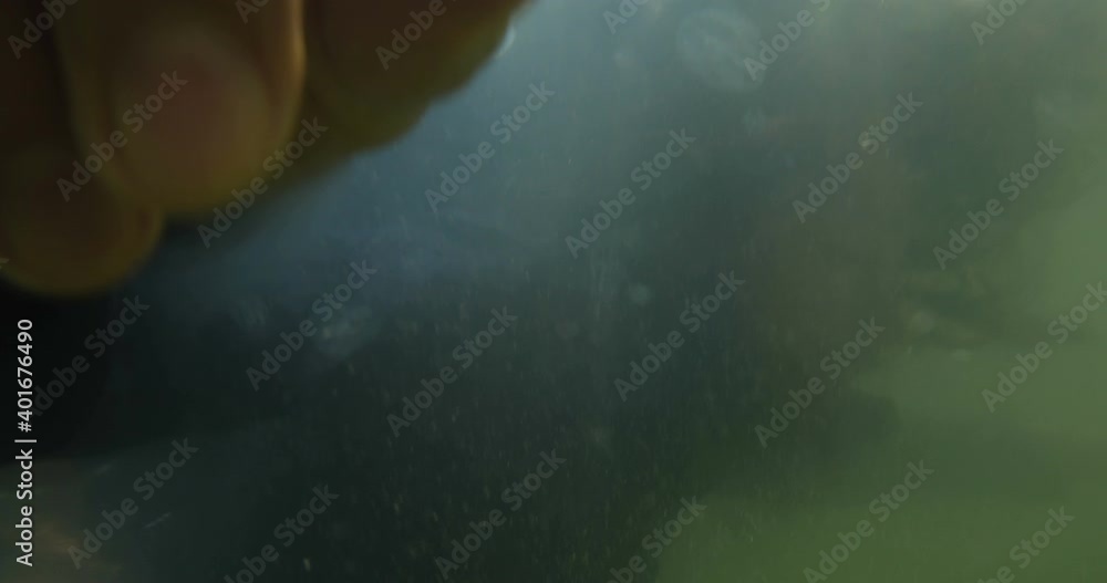 Close-up underwater shot of a long-haired man in black clothes lying in ...