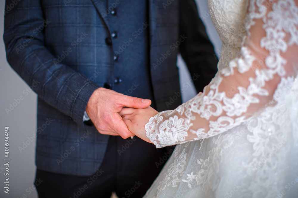 Young married couple holding hands, ceremony wedding day. The bride and ...