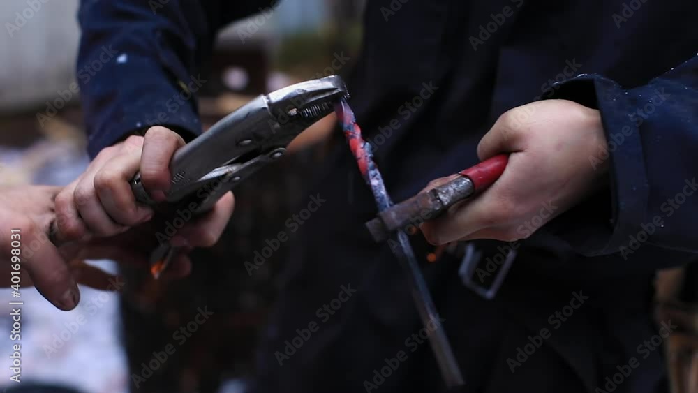 Selective focus of female blacksmith, hands making a spiral of iron ...