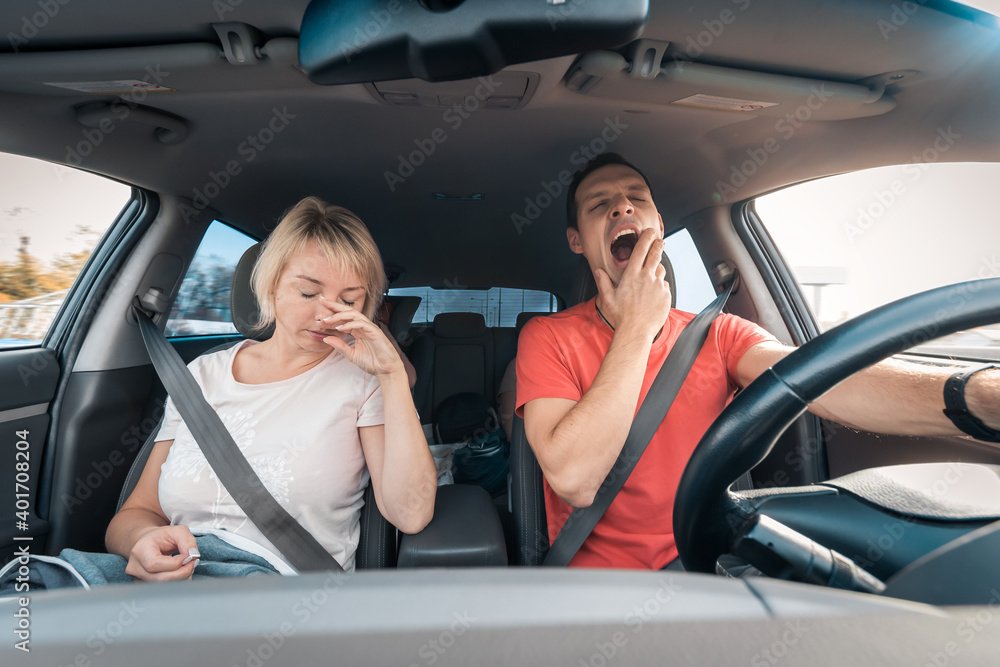 Tired and drowsy driver man yawns while next to sleeping exhausted wife ...