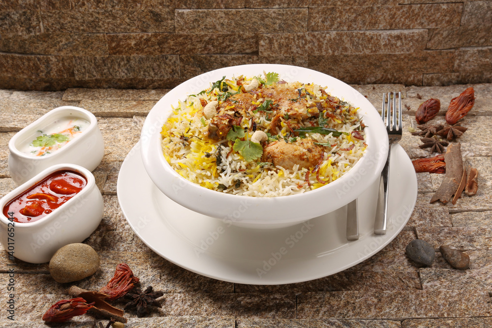 chicken biryani with pickle and yoghurt garnished with spices stone ...