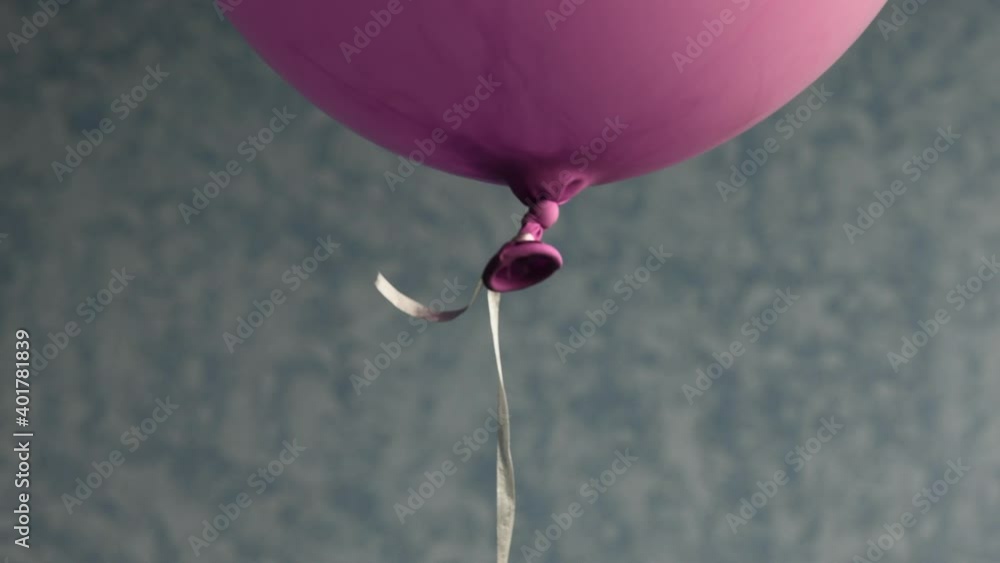 Bottom part of pink balloon with rubber tail tied with long string on ...