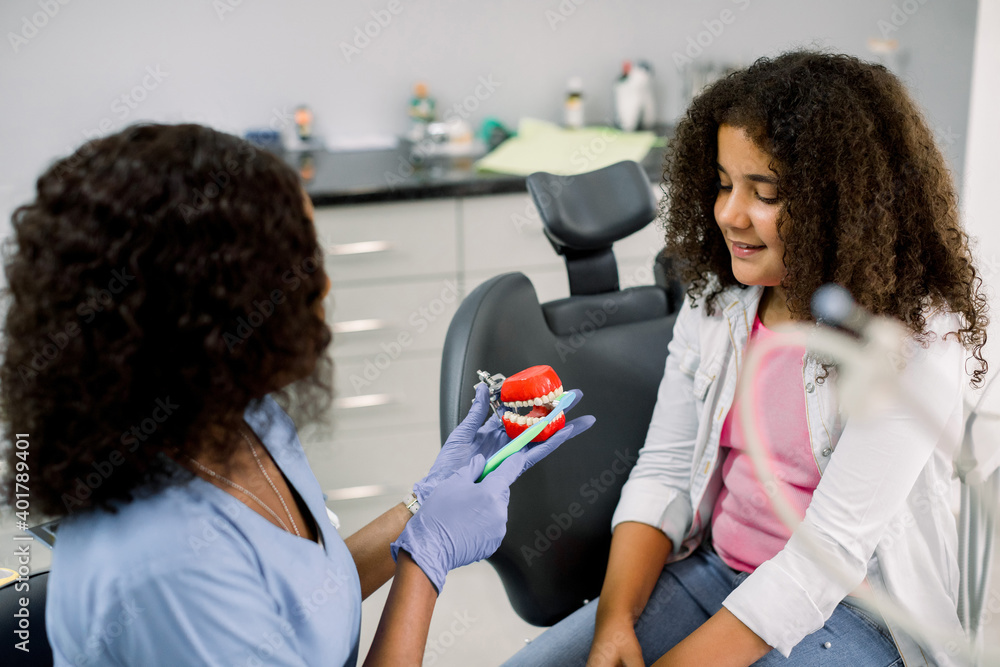 Female African doctor demonstrating proper dental care to her little ...