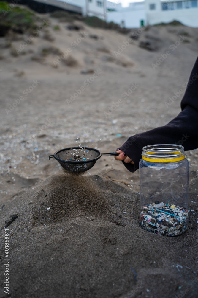 microplastics from the beach in the black metal filter and bottle with ...