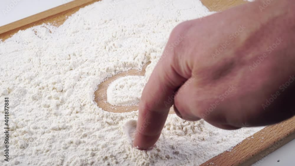 Chef draws a symbol of love heart with an arrow on a pile of flour on a ...