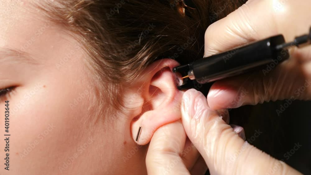 Vidéo Stock Pretty teenaged girl having her ears pierced. Female ...