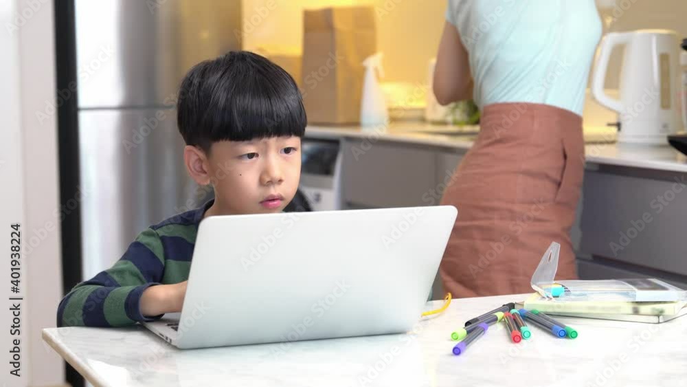 A smart asian little boy learning online at home during Covid-19 ...