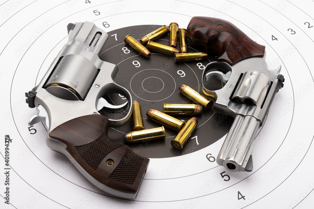Revolver hand gun pistols and bullets on bull eye target background ...