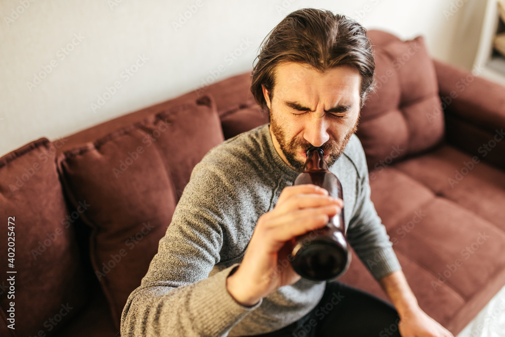 top view of young depressed drunk man drinking beer from the bottle, at ...