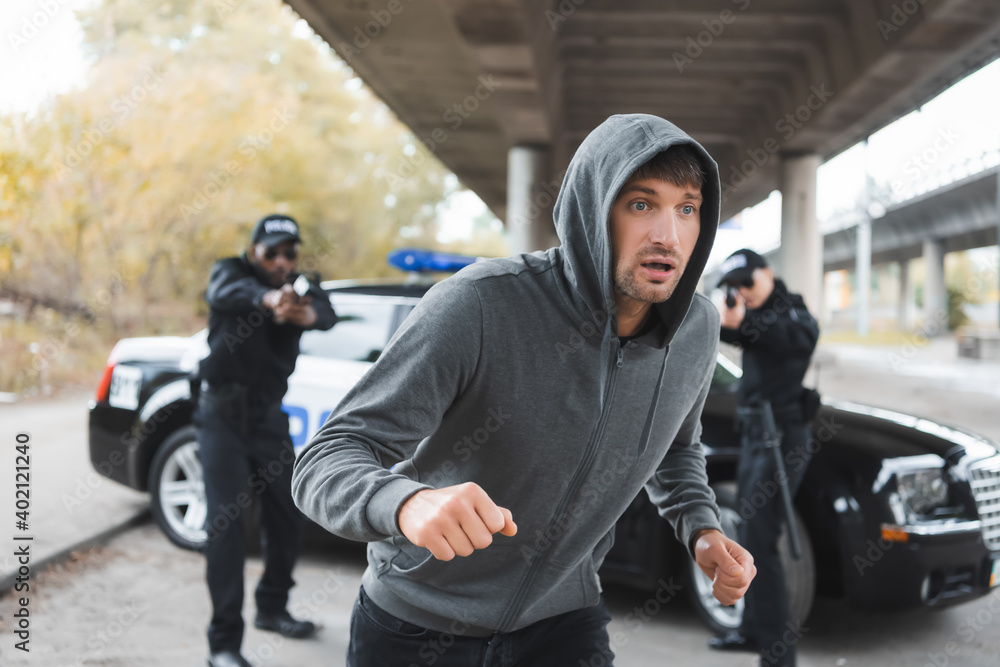 scared hooded offender running from multicultural police officers ...