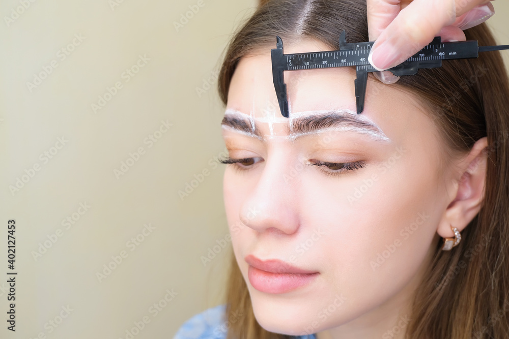 Changing shape of the eyebrows. Eyebrow stylist measuring eyebrow with ...
