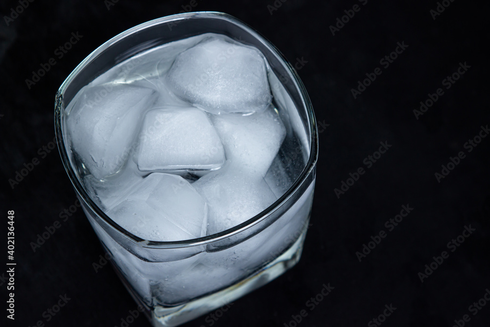 Iced water in a glass on a black background. Pieces of ice. clean ...