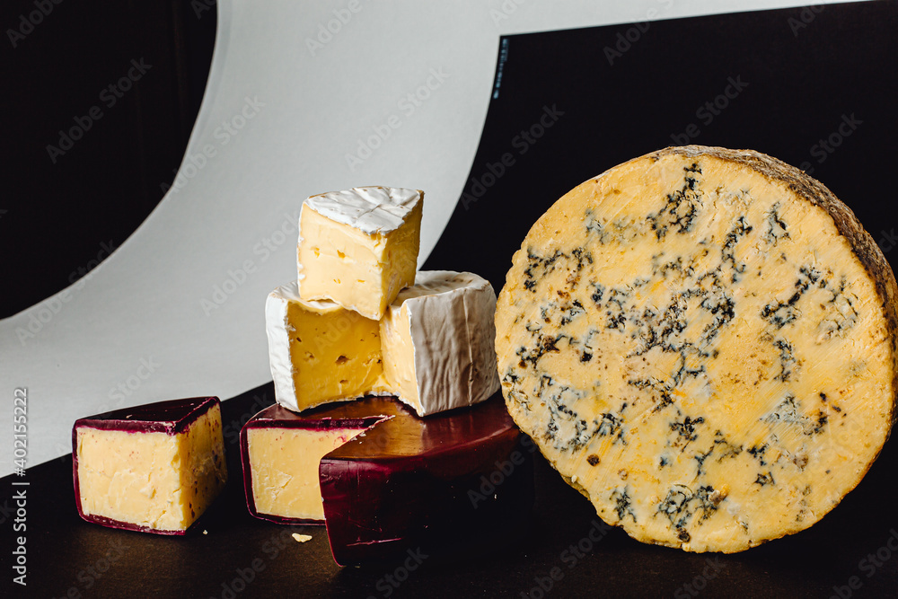 Assortment of different cheese types on dark and white background ...