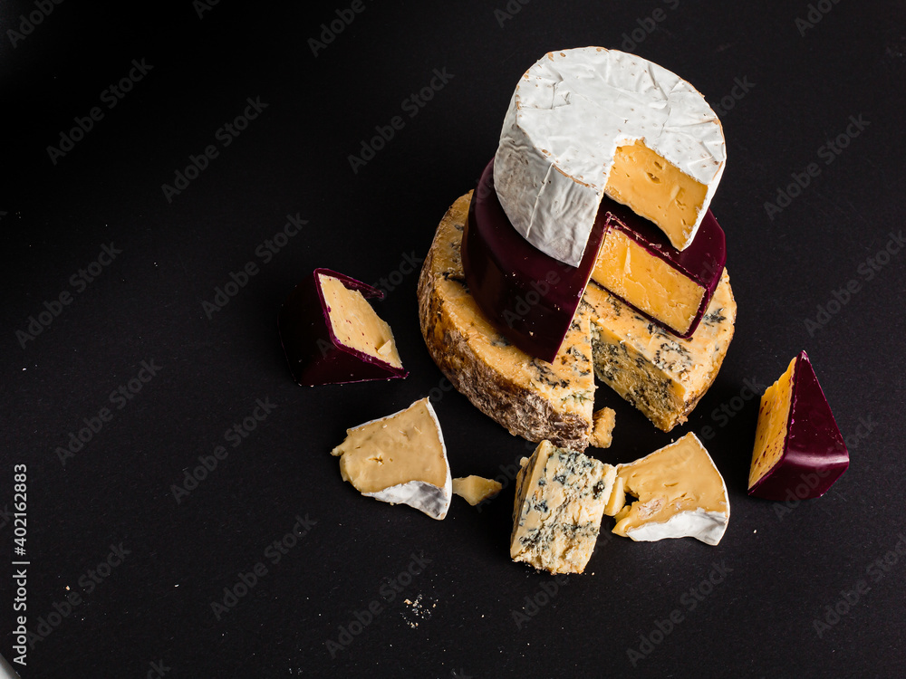 Assortment of different cheese types on dark and white background ...