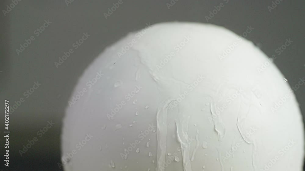 Close up of a white plain sphere wet with water running down the sphere ...