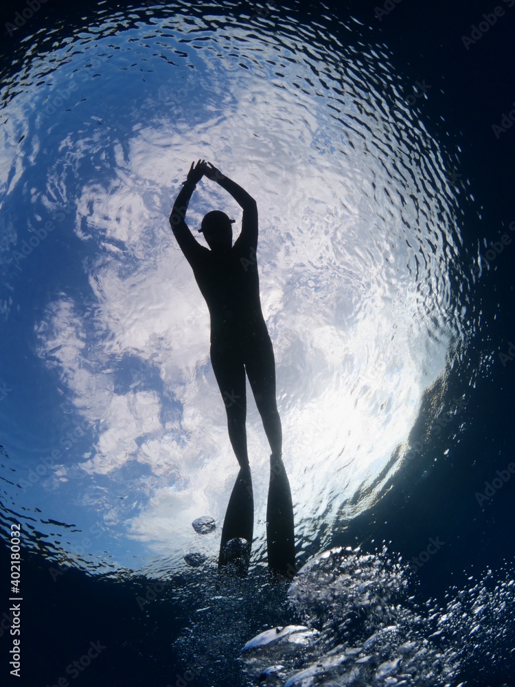 free diver swimming underwater silhouette with sky and clouds in ...