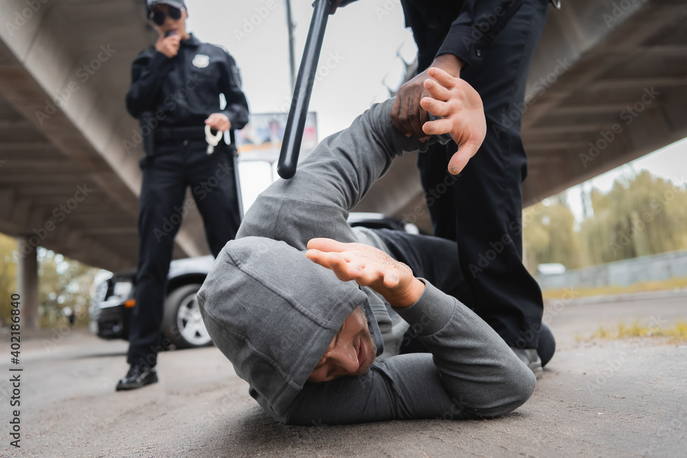 african american policeman with truncheon arresting hooded offender ...