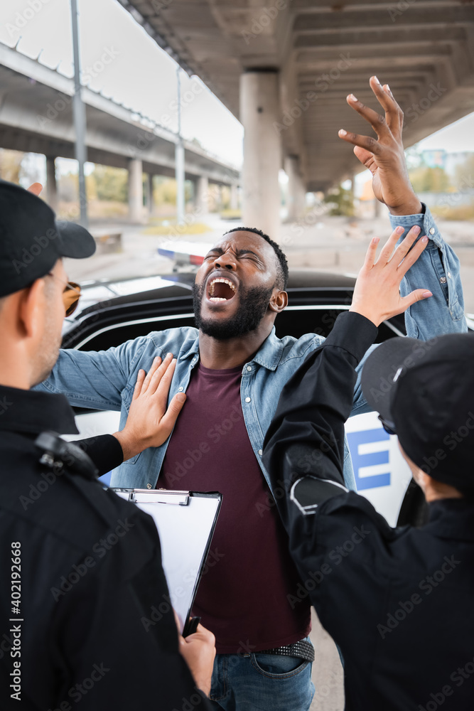 back view of police officers calming despaired african american man ...
