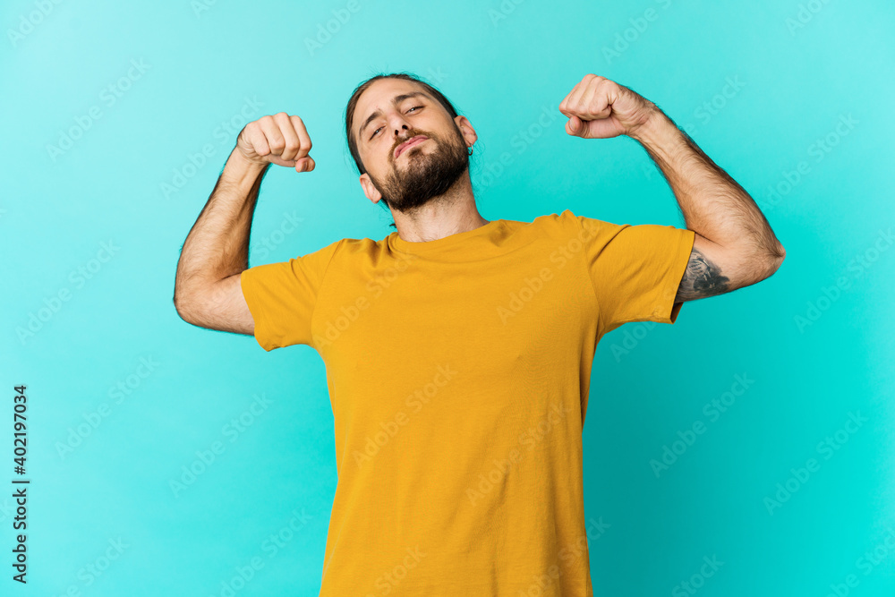 Young man with long hair look showing strength gesture with arms ...