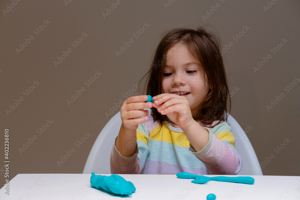 Little girl playing with colorful clay. Cute child girl sits at the ...