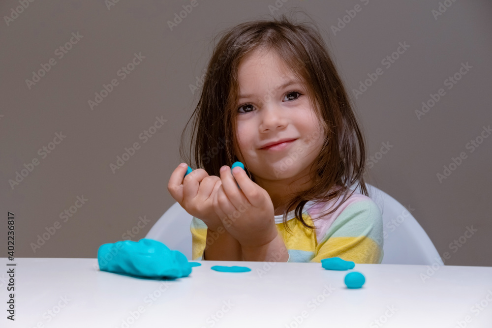 Little girl playing with colorful clay. Cute child girl sits at the ...