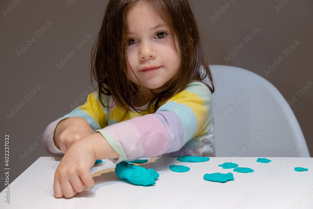 Little girl playing with colorful clay. Cute child girl sits at the ...