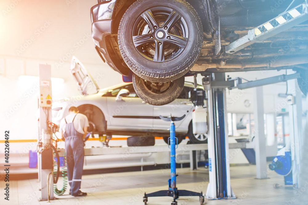 The car is lifted for repair on a lift in a car service station, a ...
