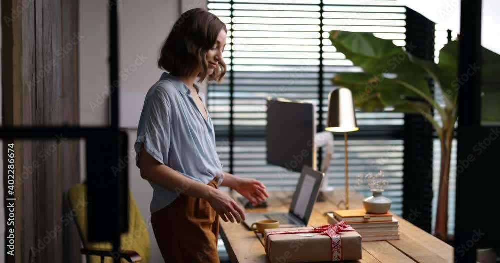 Young woman surprised seeing the gift box on the workplace in office ...