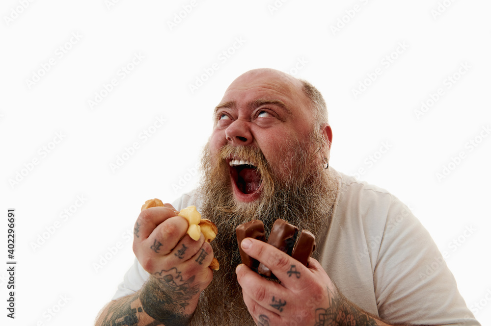 Angry overweight man squeezing eclairs and chocolate bars into his ...