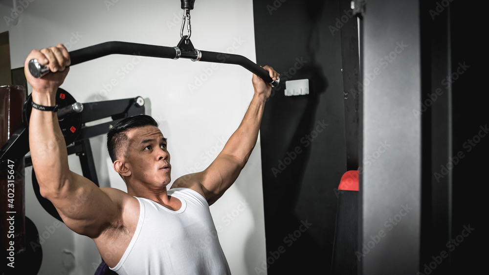 A fit and clean cut asian man doing lat pulldowns at the gym. Working ...