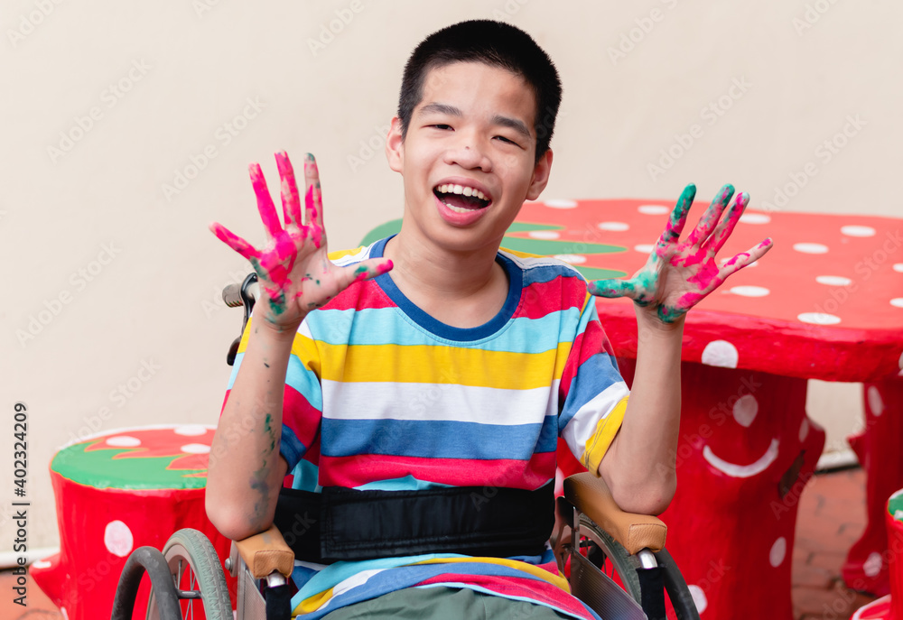 Asian disabled child on wheelchair smiling with his hands were stained ...