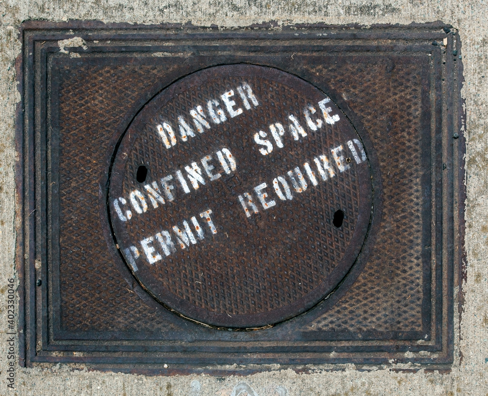 DANGER CONFINED SPACE PERMIT REQUIRED warning message on manhole cover ...