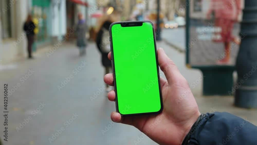 Close up hands man using phone with vertical green screen background street city blurred ...