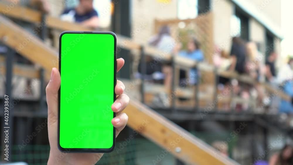 Close up hands woman holding phone with vertical green screen on busy ...