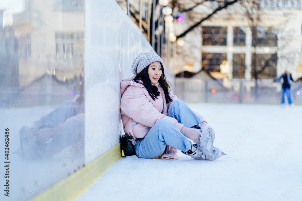 Foto de Ice skating concept. Surprise emotion asian woman sitting on ...