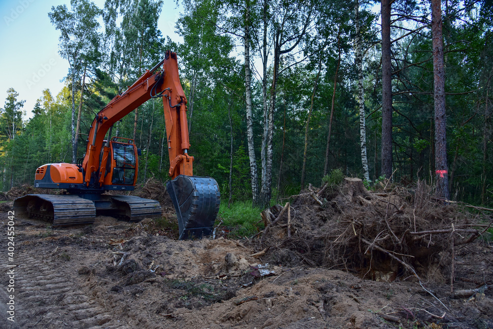 Excavator clearing forest for new development. Orange Backhoe modified ...