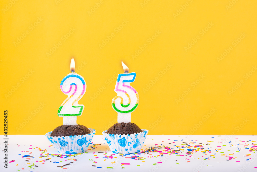 25 number candle on a cup cake with colorful sprinkles and yellow ...